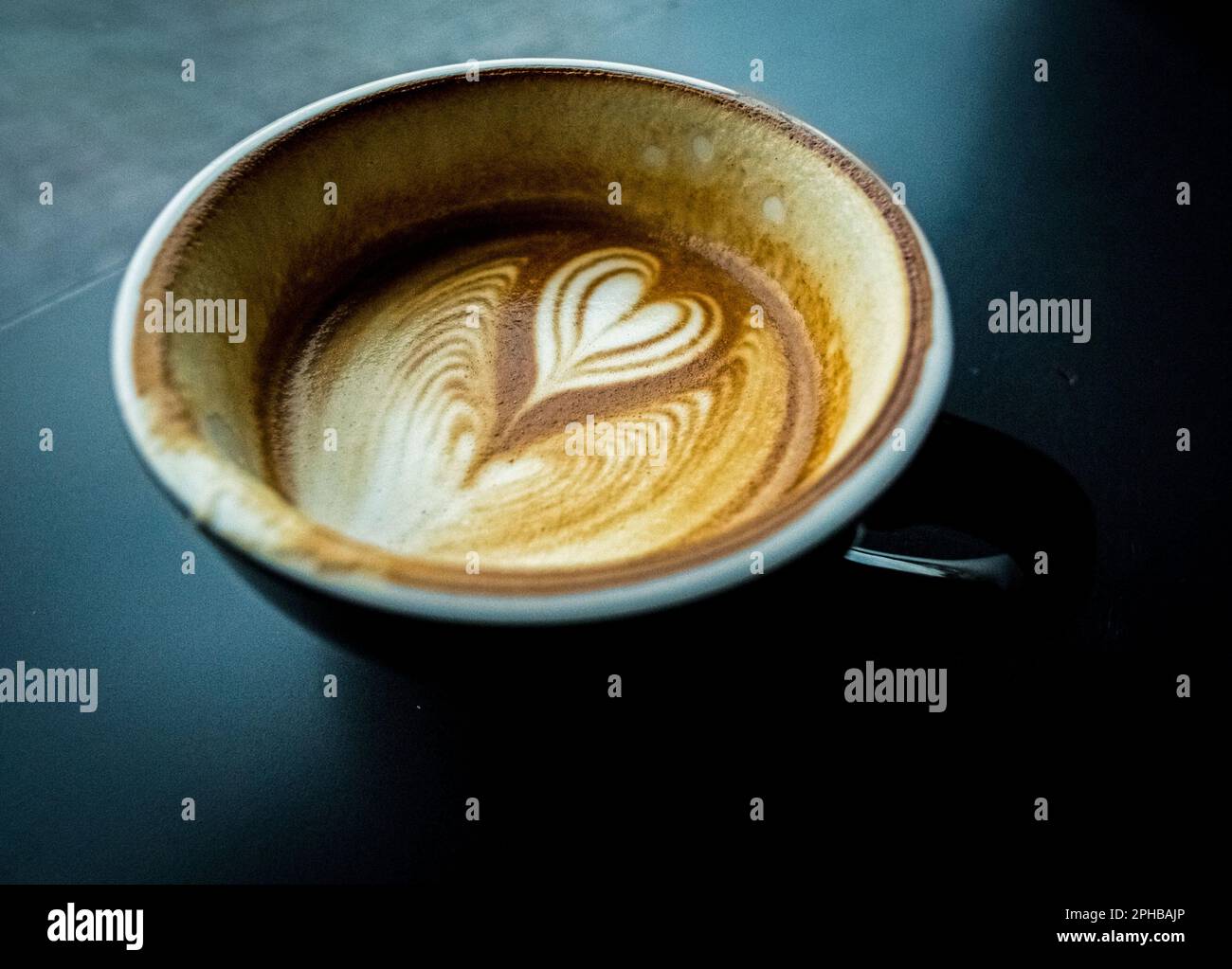 cup of hot latte coffee with love heart shape foam milk over dark ...