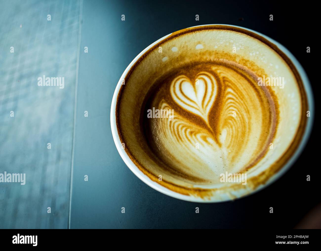 cup of hot latte coffee with love heart shape foam milk over dark ...