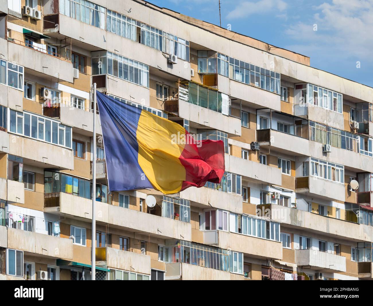 Romanian national flag in the wind and a worn out communist apartment ...