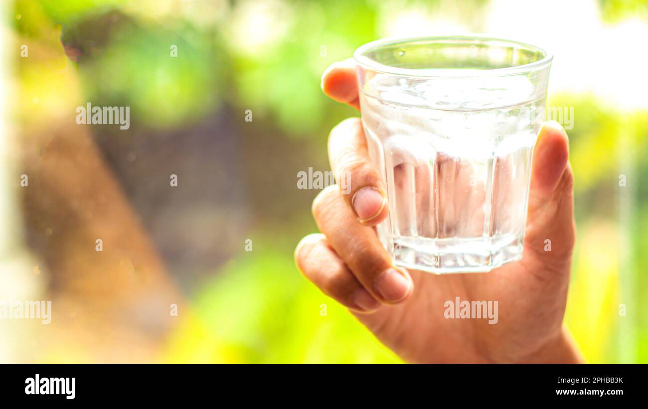 hand holds clear water in glass . hand holding A clear glass of clean ...