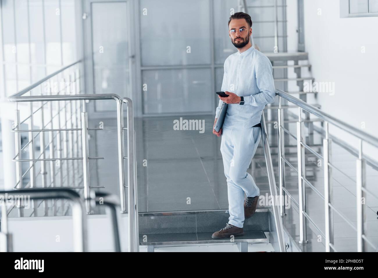 Using phone. Young handsome man in formal clothes indoors in the office ...