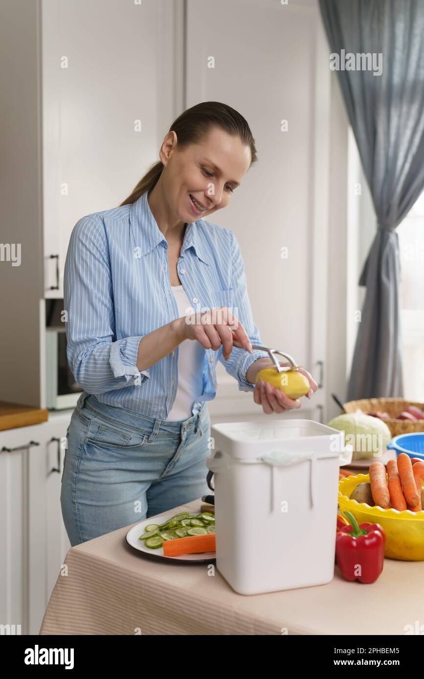 Happy white woman peeling potato and composting leftovers. Responsible ...