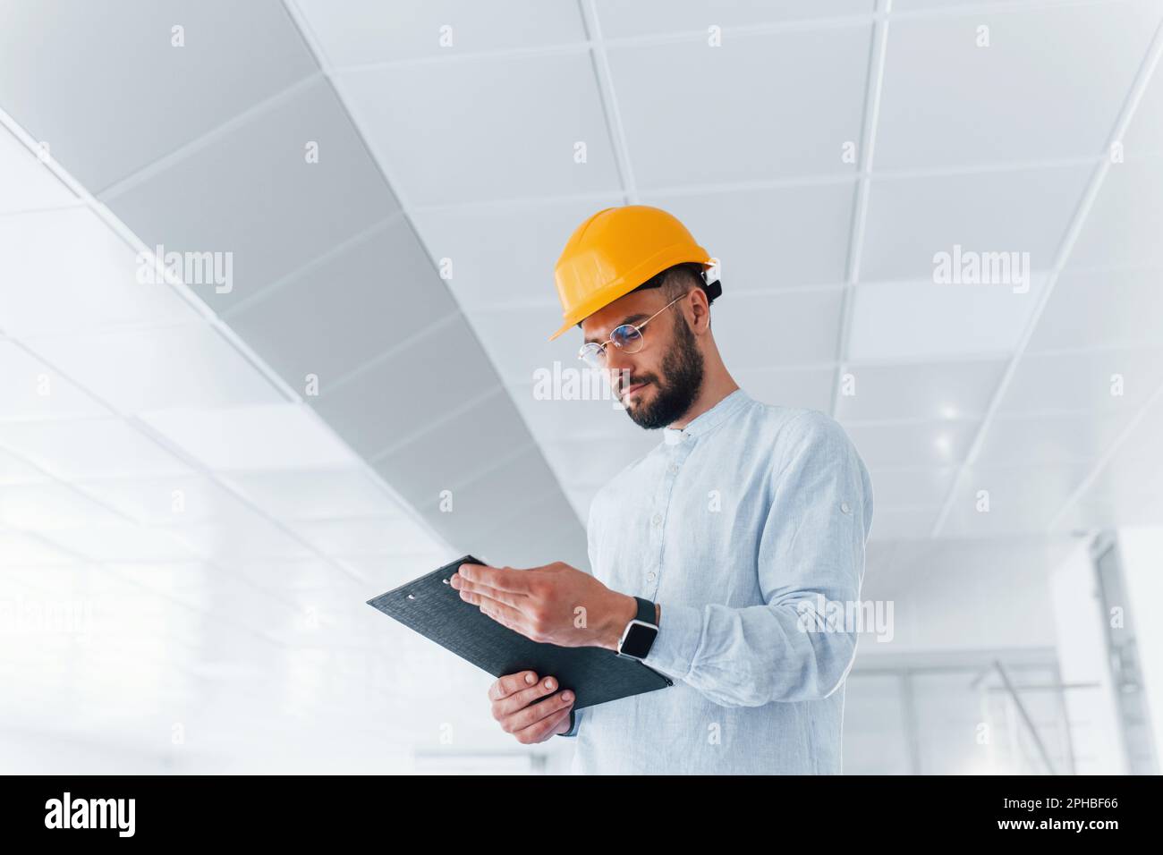 Front view of engineer in white clothes and orange protective hard hat ...
