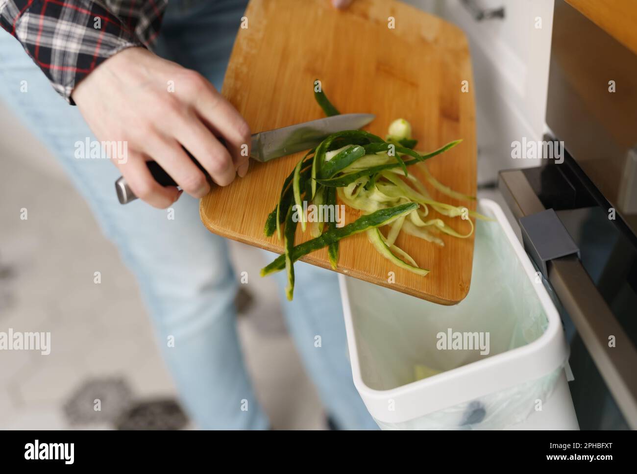 Woman throwing cucumber skin peels into composter container. Female ...