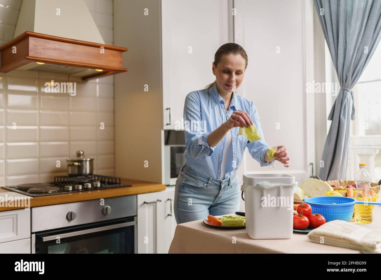 Cheerful white woman makes compost at home. House wife cooking lunch ...