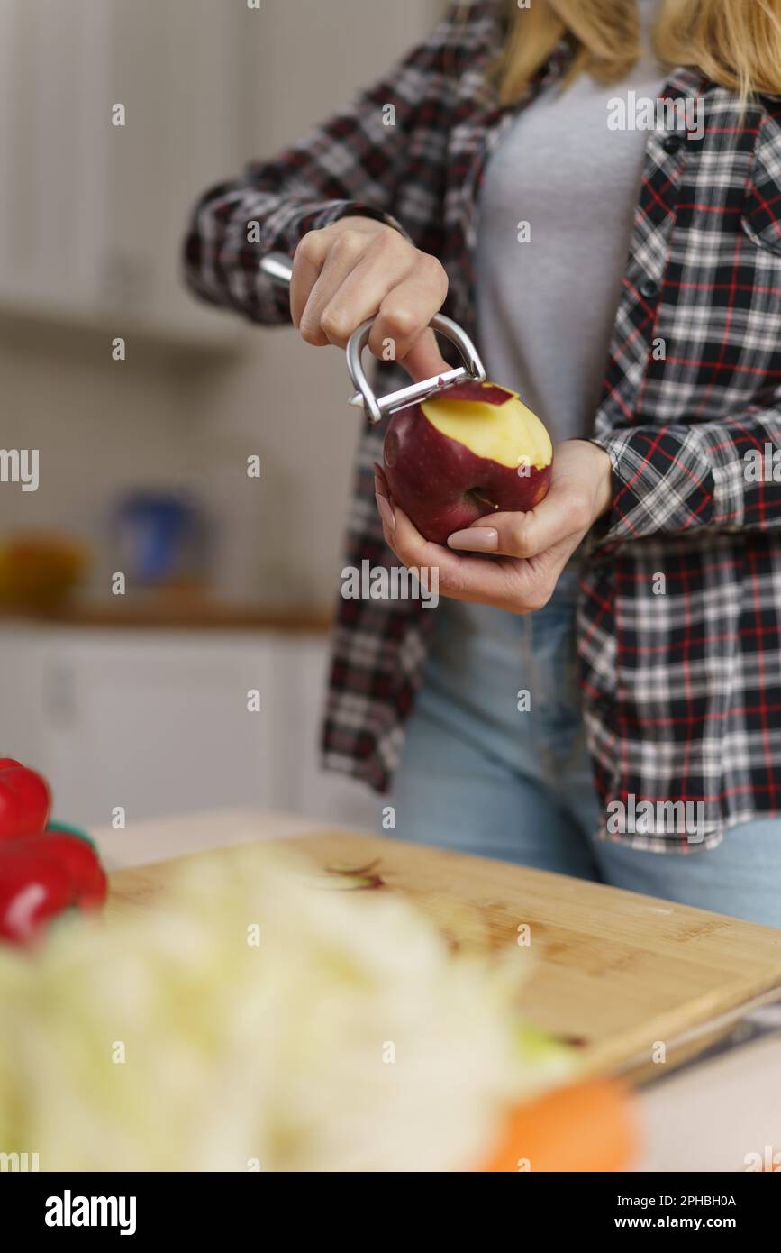 Woman peeling apple skin with peeler tool in close up. Unrecognizable ...