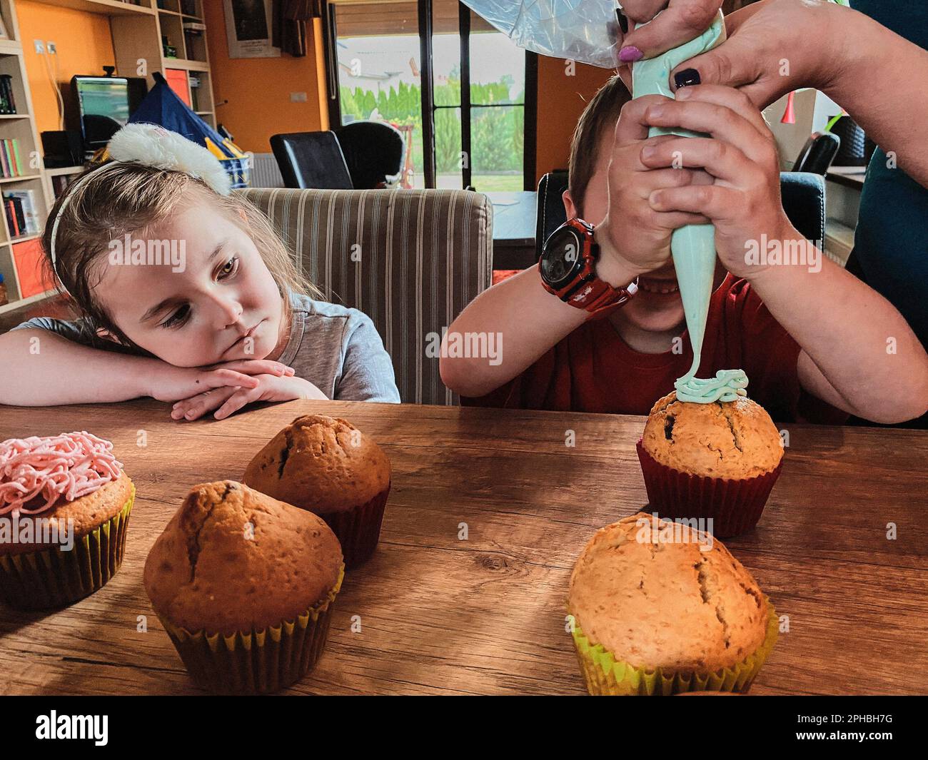 Group of children baking cupcakes, squeezing cream from confectionery ...
