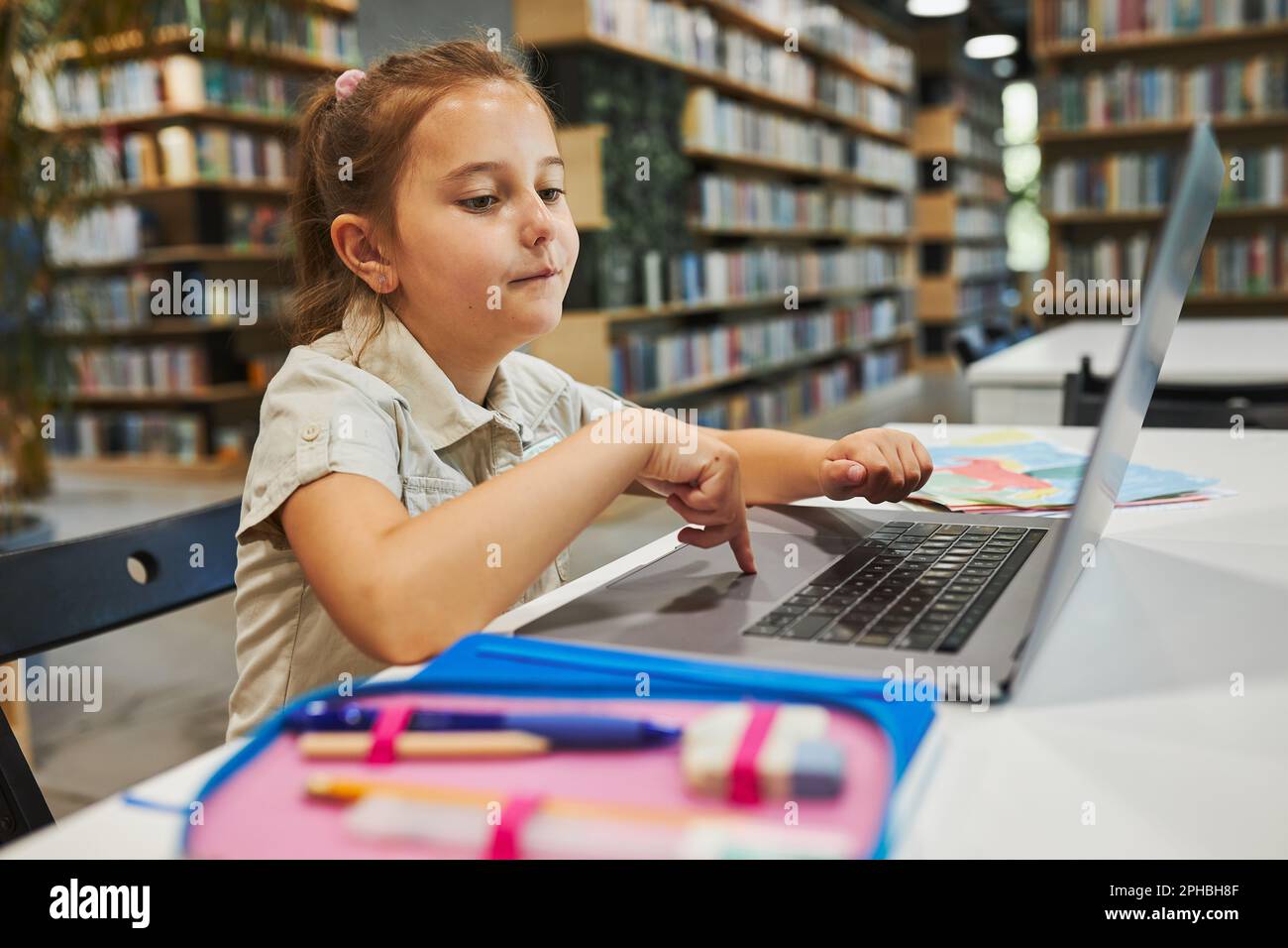 Positively engaged student doing her homework using laptop in after ...