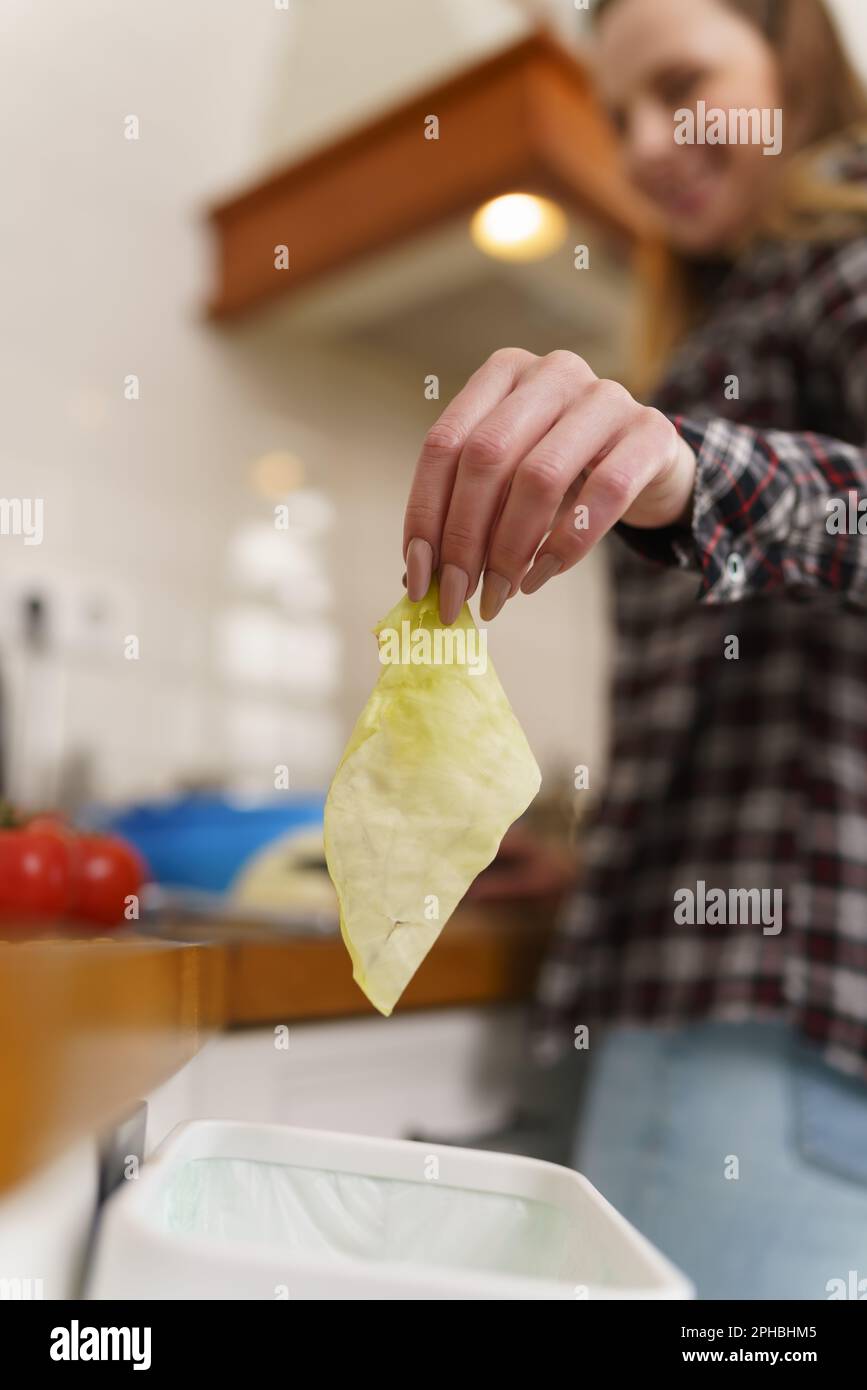 Woman throwing cabbage leaf into bokashi bin for compost. Responsible ...