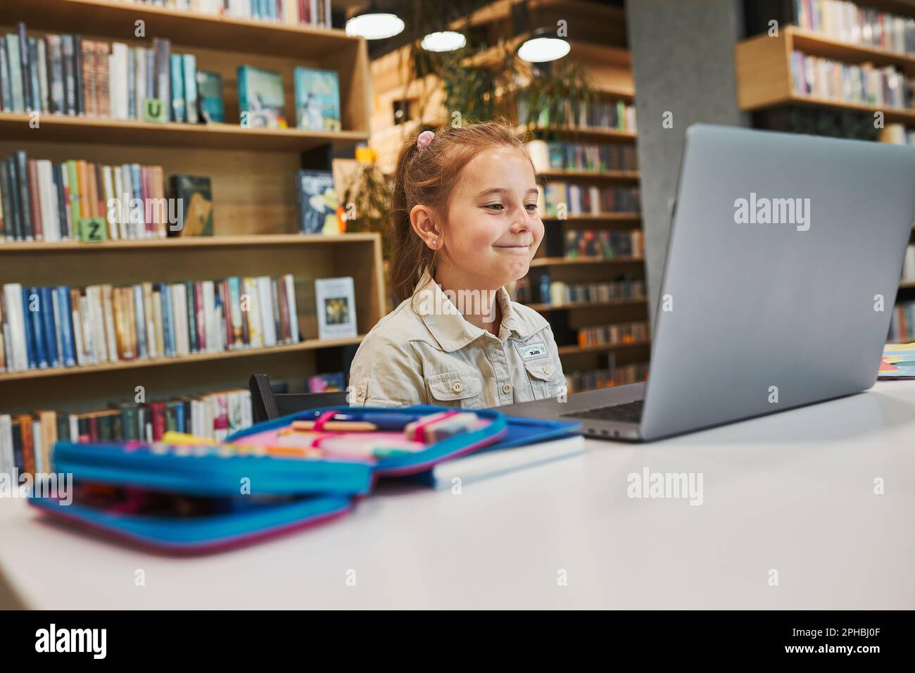 Pleased little student having video class remotely with her teacher on ...
