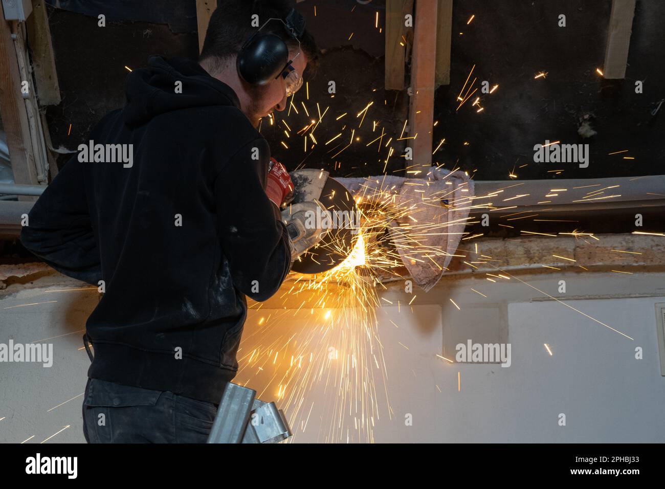 Man working with an angle grinder is engulfed by sparks flying off from ...