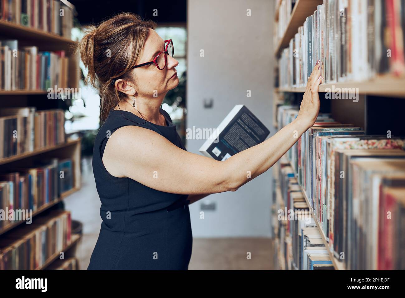 Woman looking for books in public library. Teacher searching for ...