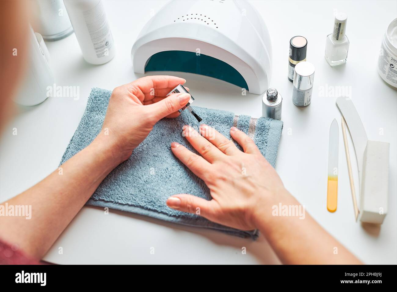 Woman applying gel hybrid polish using UV lamp. Beauty wellness spa ...