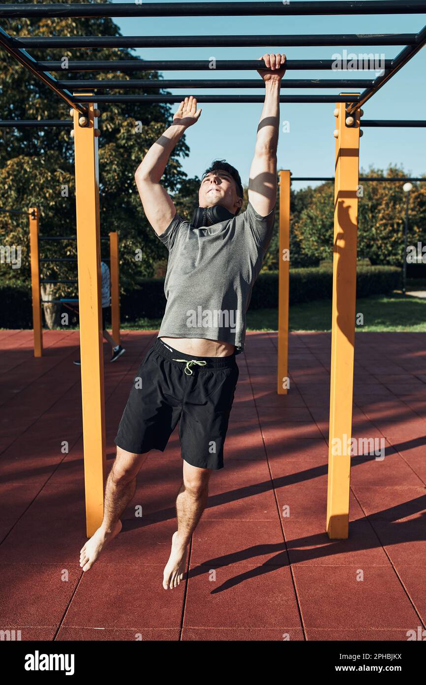 Young man bodybuilder exercising on monkey bars during his workout in a ...