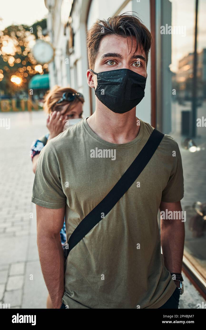 Young man walking along a store front in the city center in the evening ...