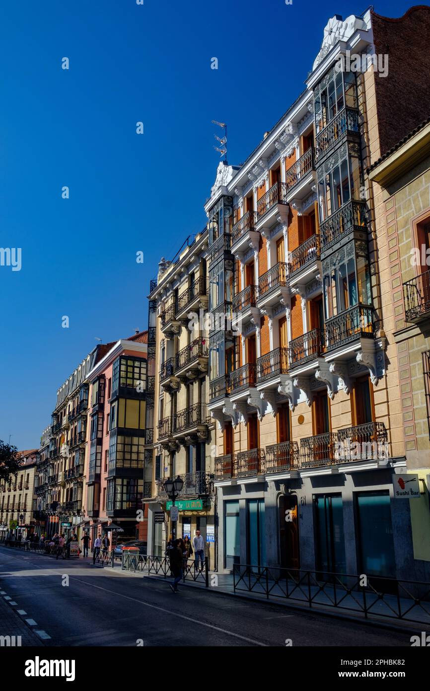 A bustling street in a cityscape featuring a row of tall buildings ...