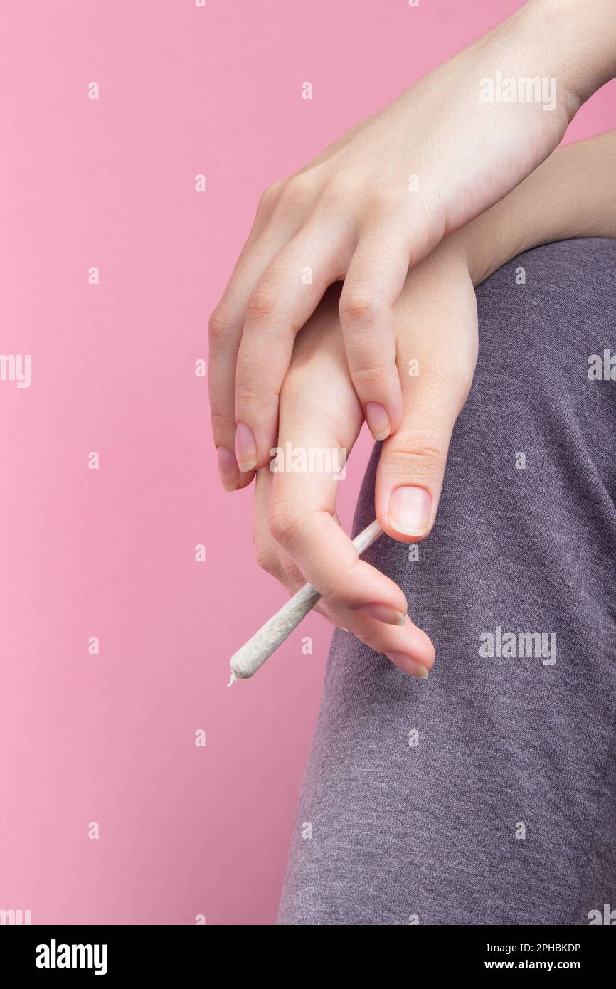 Female hands lie on her knee, pinch a joint with medical marijuana ...