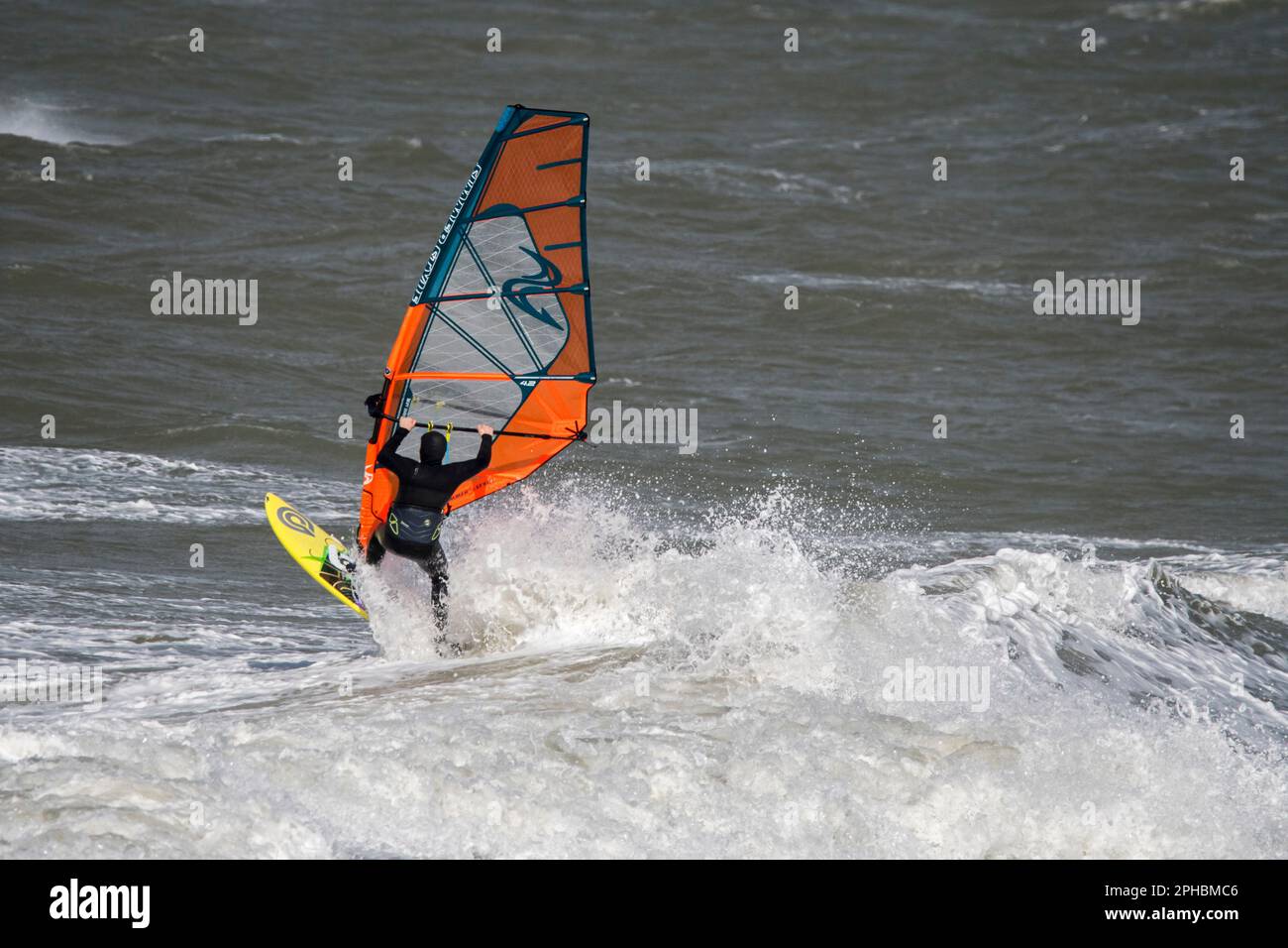 Recreational windsurfer in black wetsuit practising classic windsurfing ...