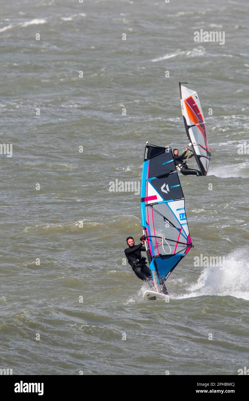 Two recreational windsurfers in black wetsuits practising classic ...