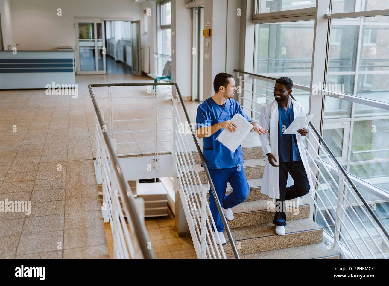 Full length of male doctor and nurse discussing over documents while ...
