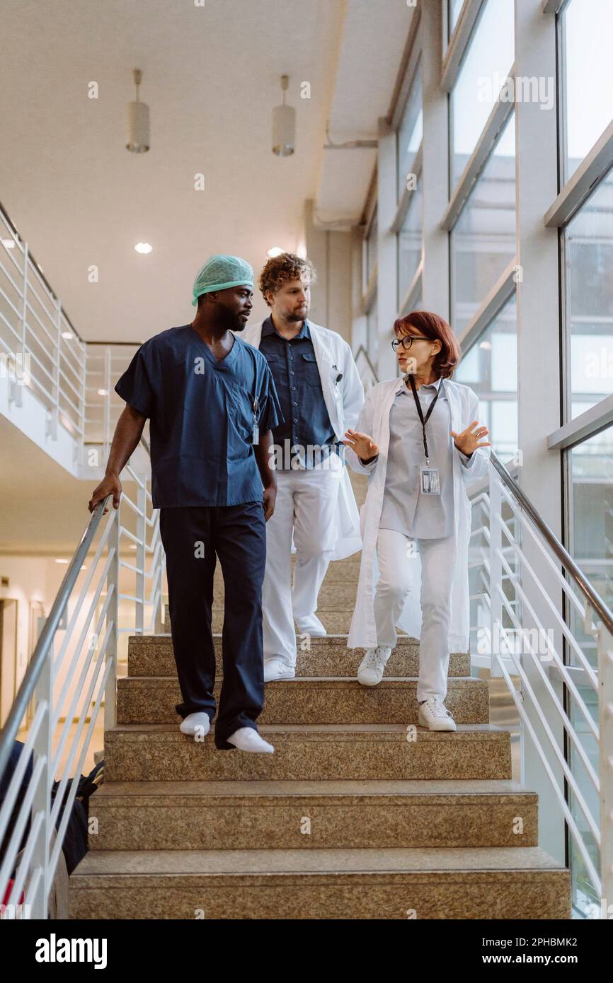 Low angle view of senior female doctor discussing with colleagues while ...