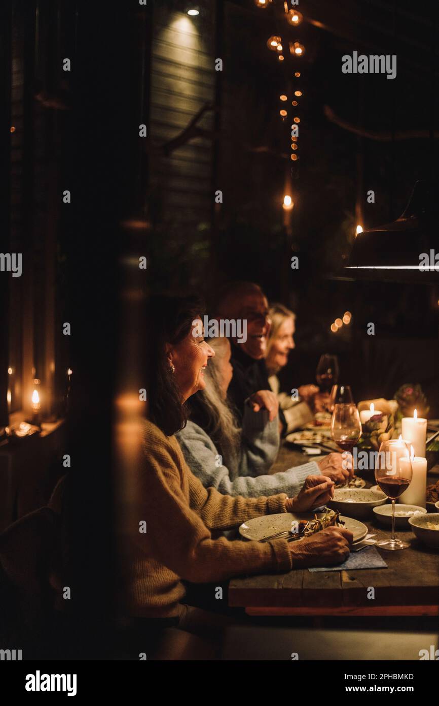 Male and female senior friends enjoying candlelight dinner together ...