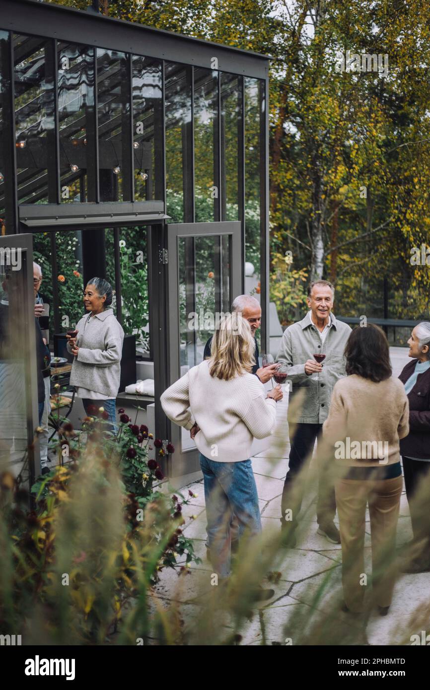Happy friends talking to each other during dinner party at backyard ...