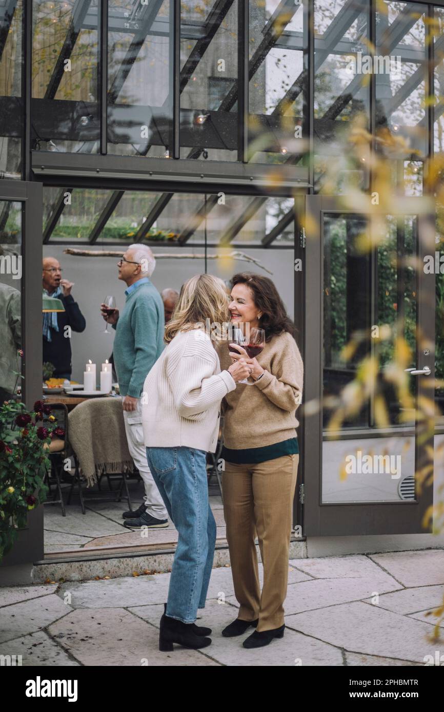 Happy female senior friends greeting each other at dinner party in ...