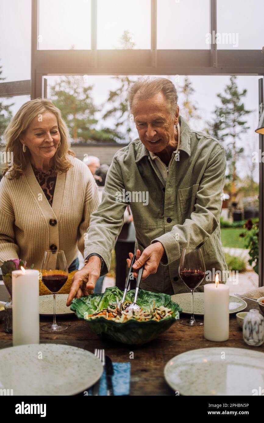 Senior man preparing dining table with female friend during party Stock ...
