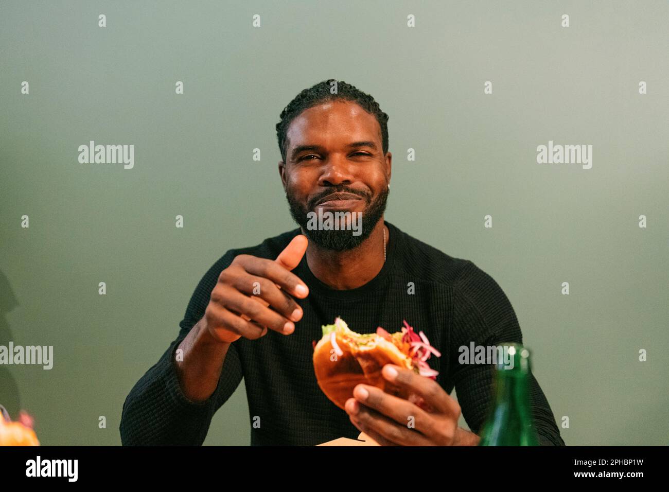 Portrait of smiling man eating burger at restaurant Stock Photo - Alamy