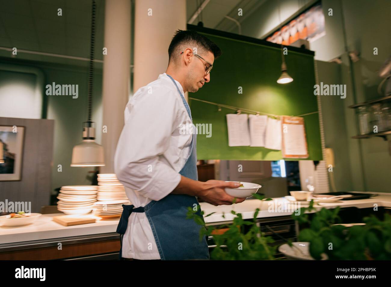 Side view of male chef holding bowls while walking in commercial ...