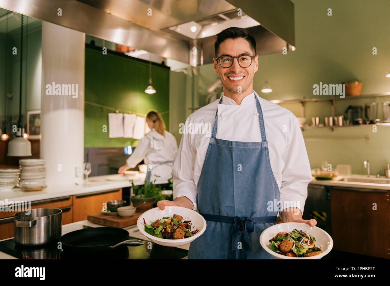 Portrait of confident male chef showing food while standing in ...
