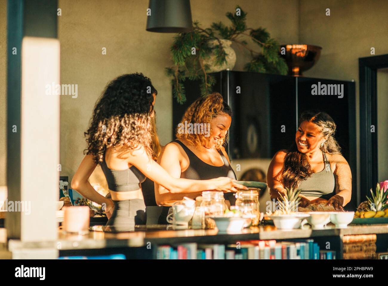 Happy female friends talking to each other while having breakfast at ...