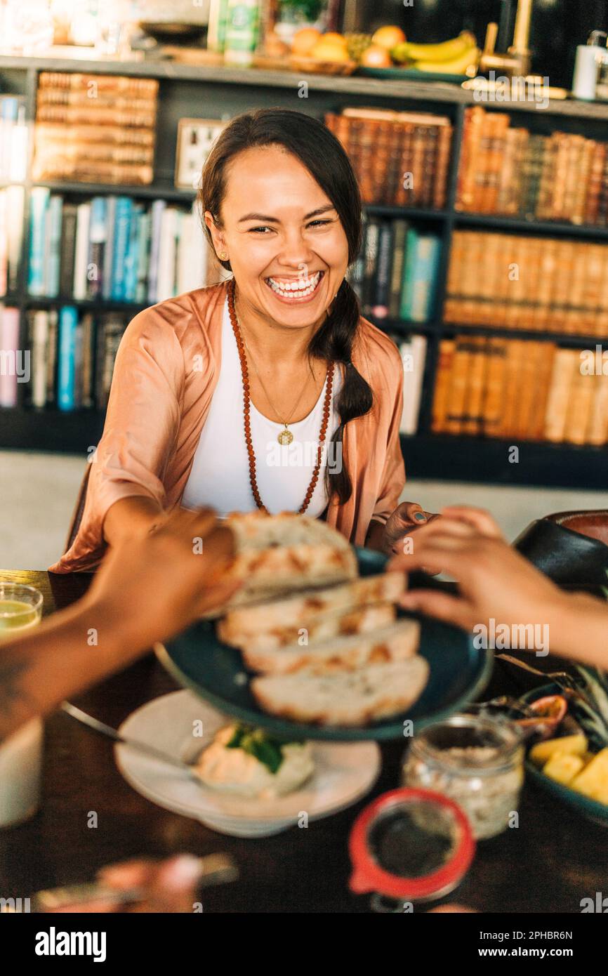 Happy woman giving food to female friends at retreat center Stock Photo ...
