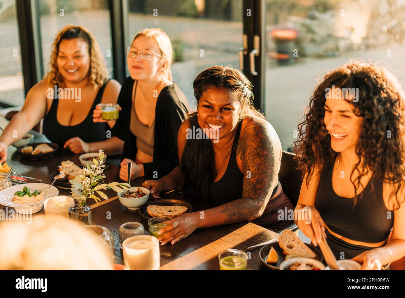 Happy female friends enjoying breakfast together at retreat center ...