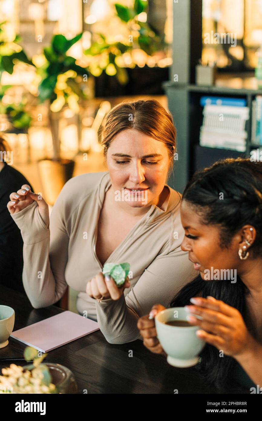 Woman showing crystal to female friend at retreat center Stock Photo ...