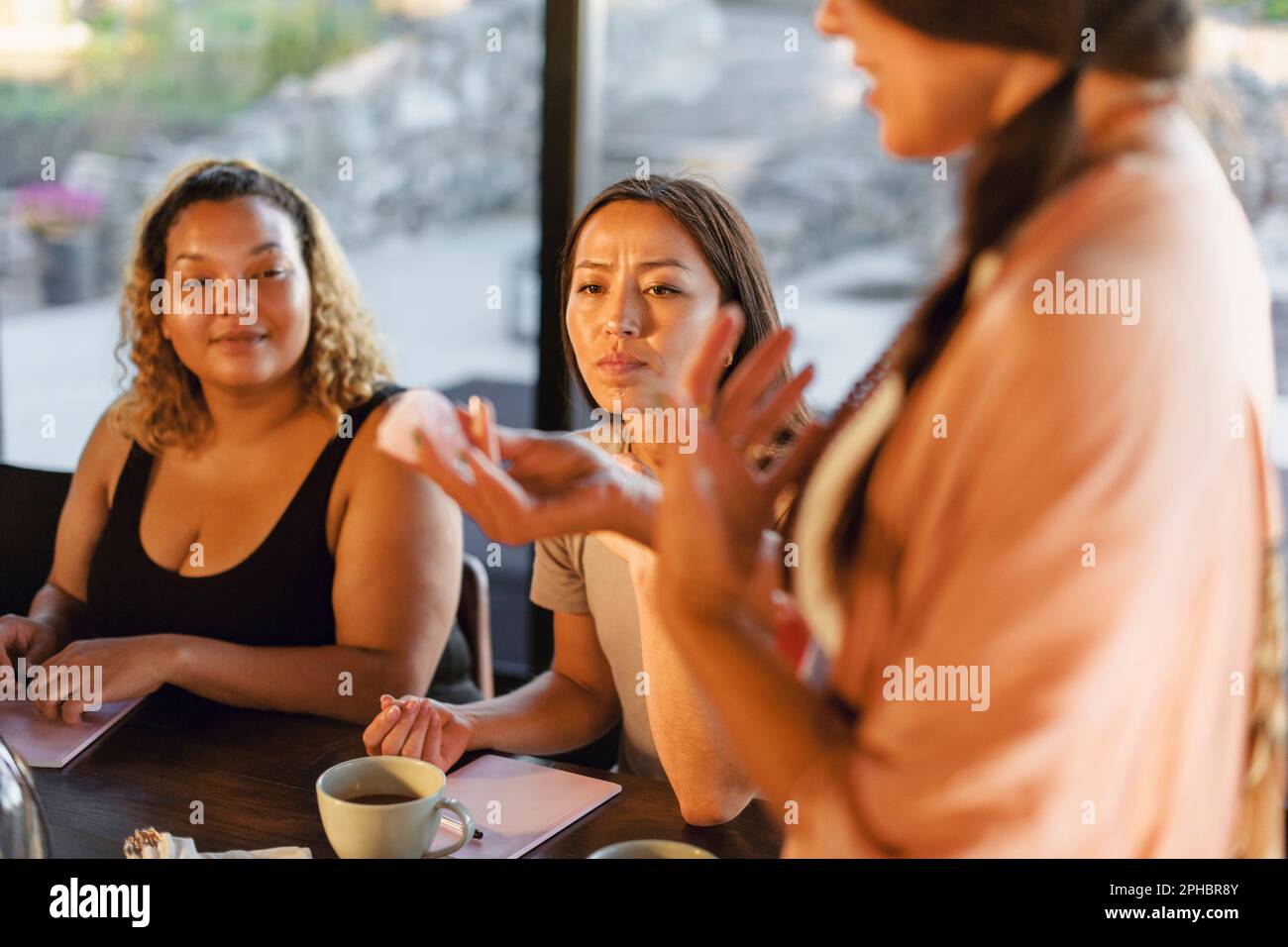 Woman explaining crystal to female friends at retreat center Stock ...