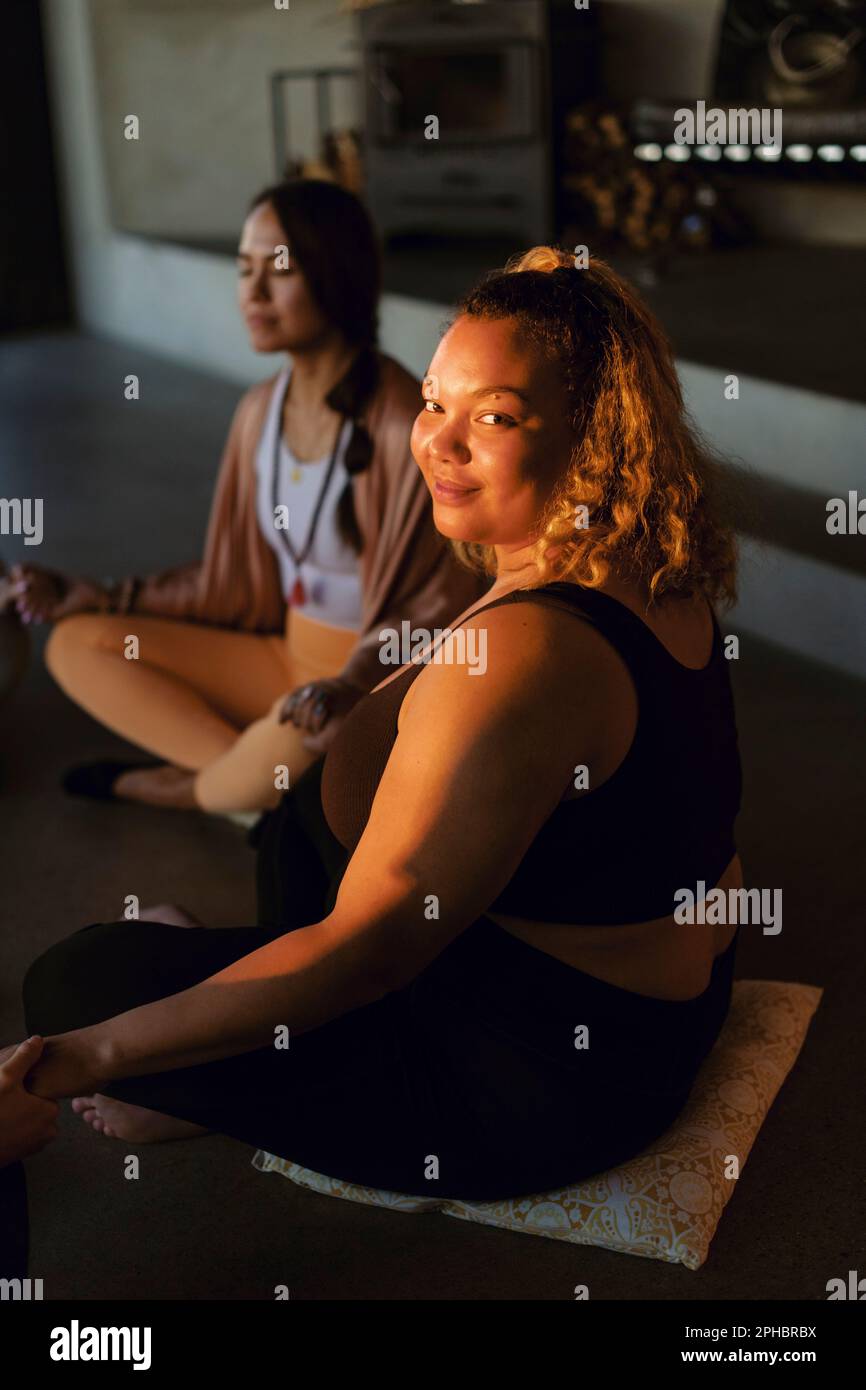 Portrait of smiling plus size woman sitting with female friend at ...