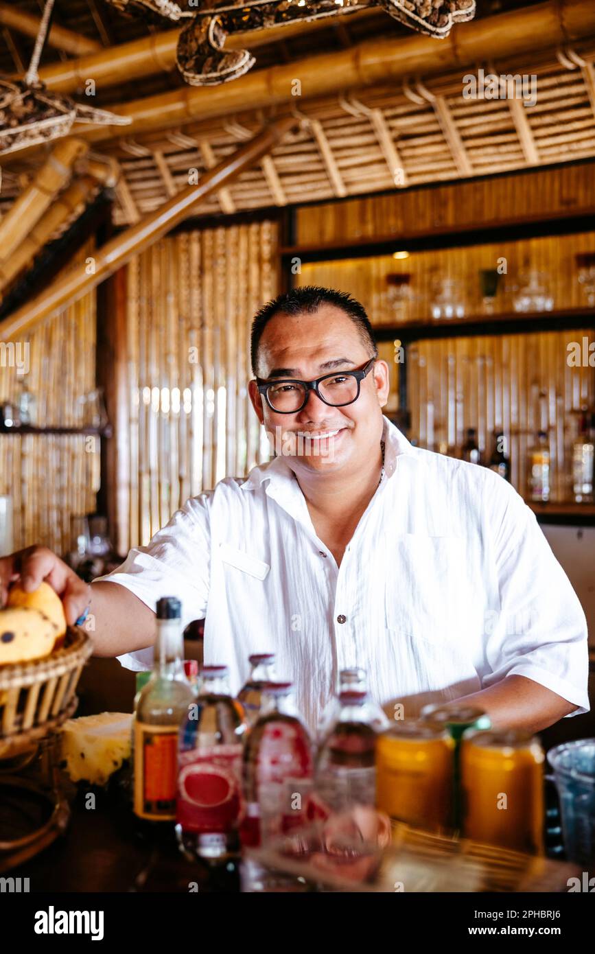 Portrait of smiling bartender with eyeglasses at counter in resort ...