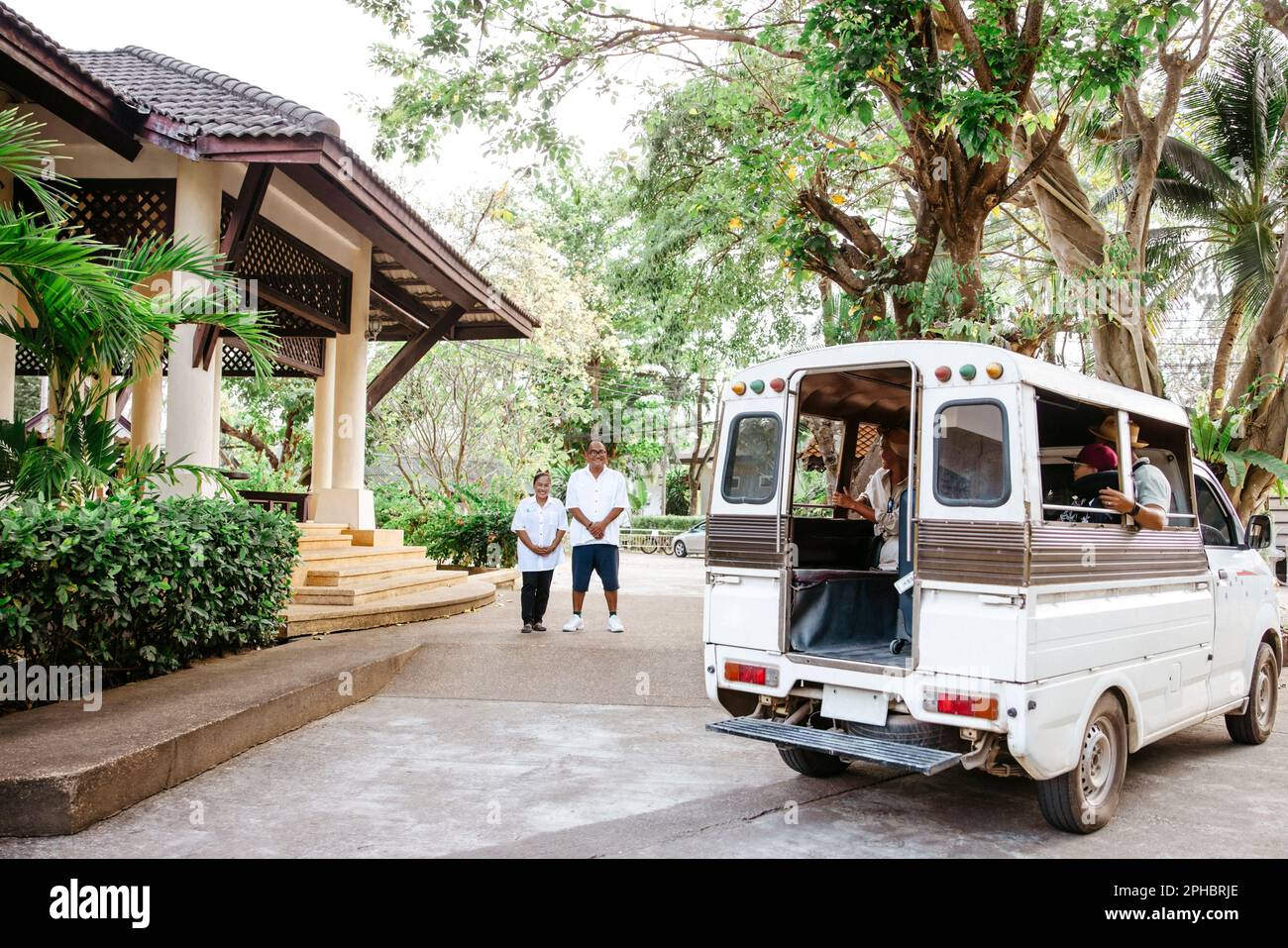 Male and female owners looking at tourists sitting inside van at resort ...