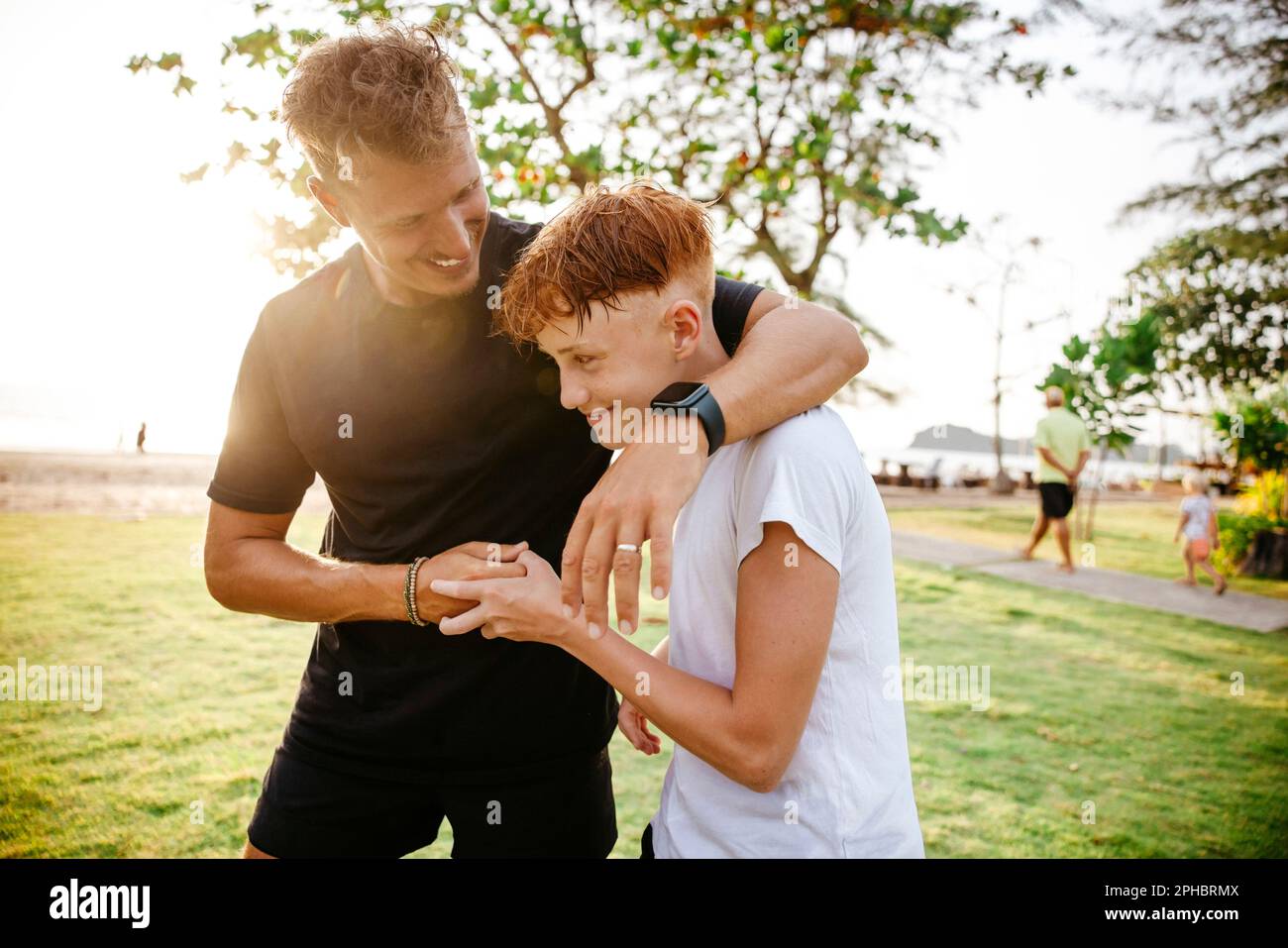 Happy father with arm around son enjoying in park during sunset Stock ...