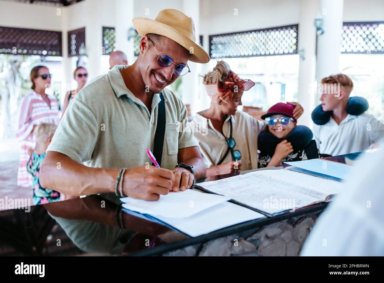 Happy man filling form at resort reception desk during vacation Stock ...
