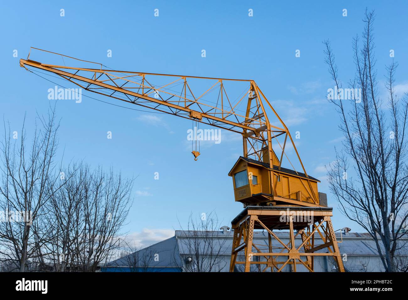 A yellow industrial crane against a blue sky near the waterfront docks ...