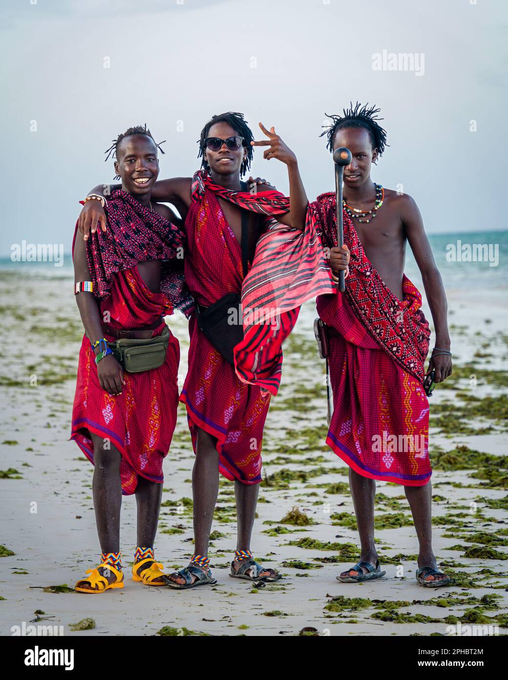 Three happy Tanzanian men in traditional clothing, standing together on ...