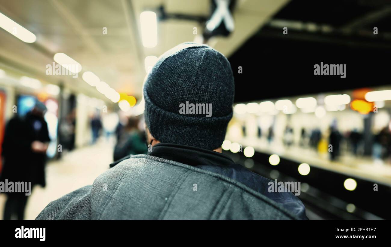 Commuter waiting for train to arrive standing at platform. Back of ...