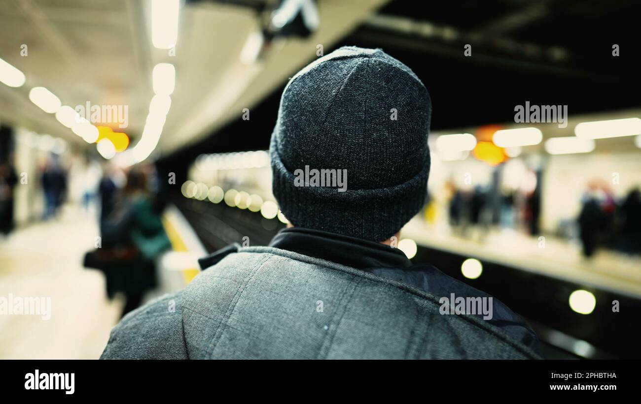 Commuter waiting for train to arrive standing at platform. Back of ...