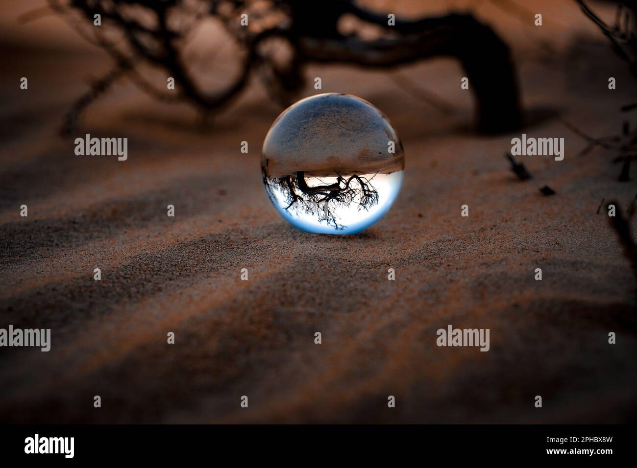 A glass ball resting on sands in a natural environment, with blurred ...