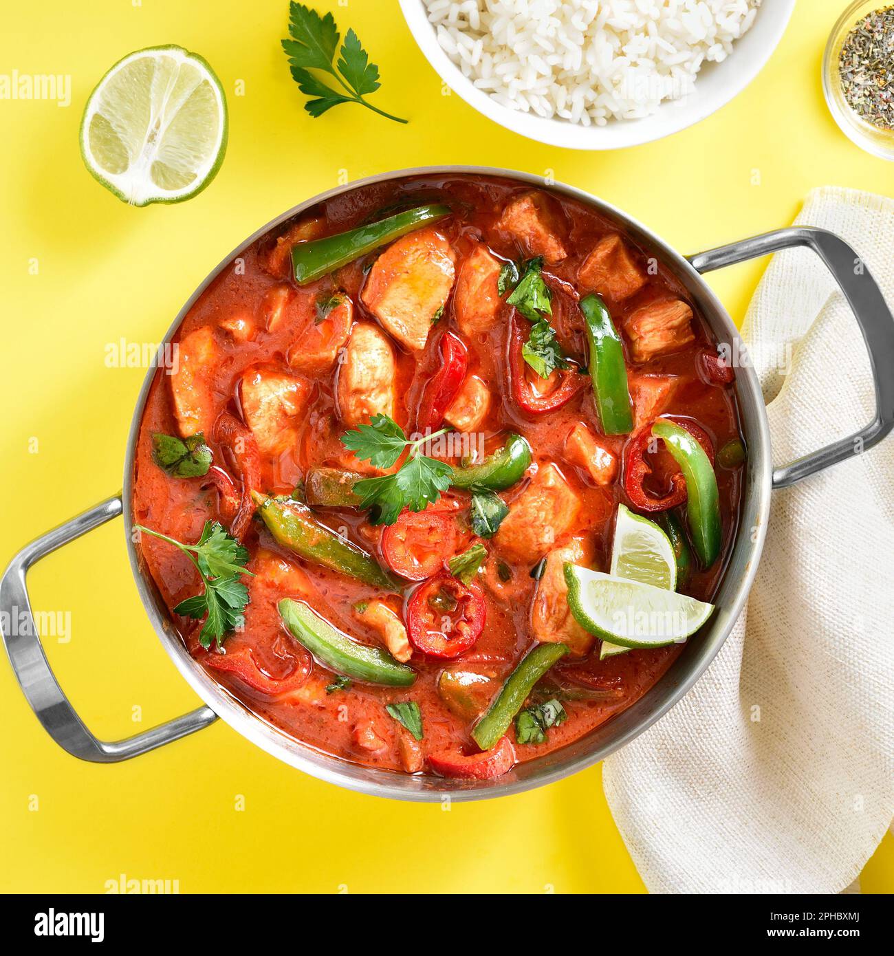 Thai style red chicken curry with vegetables in pan over yellow ...
