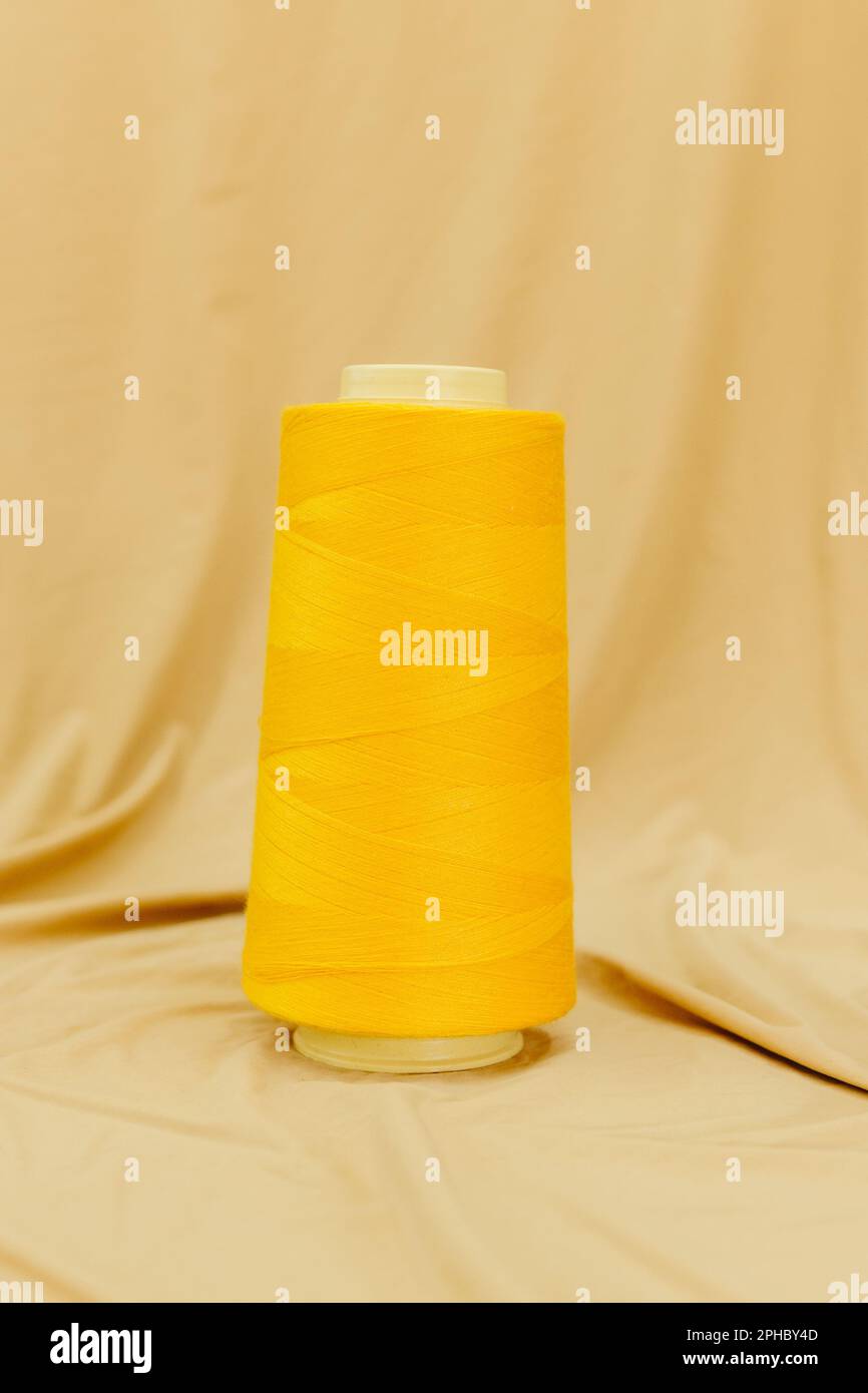A vertical close-up photograph of a yellow spool of thread Stock Photo ...