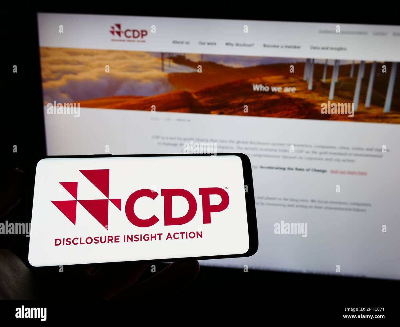 Person holding cellphone with logo of organization Carbon Disclosure ...